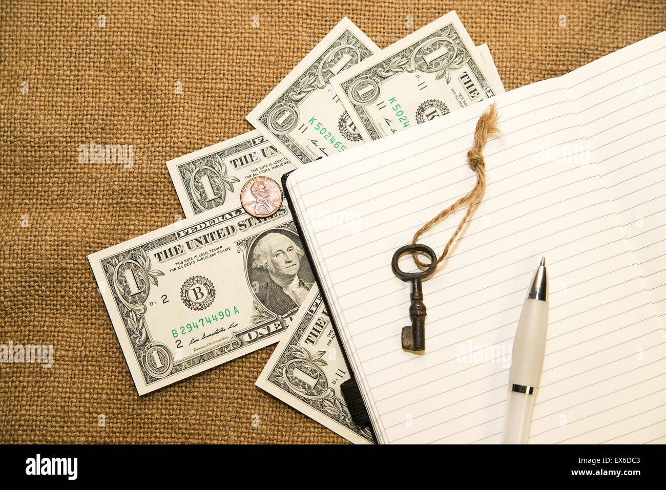 Opened notebook with a blank sheet, pen, key and money on the old ...