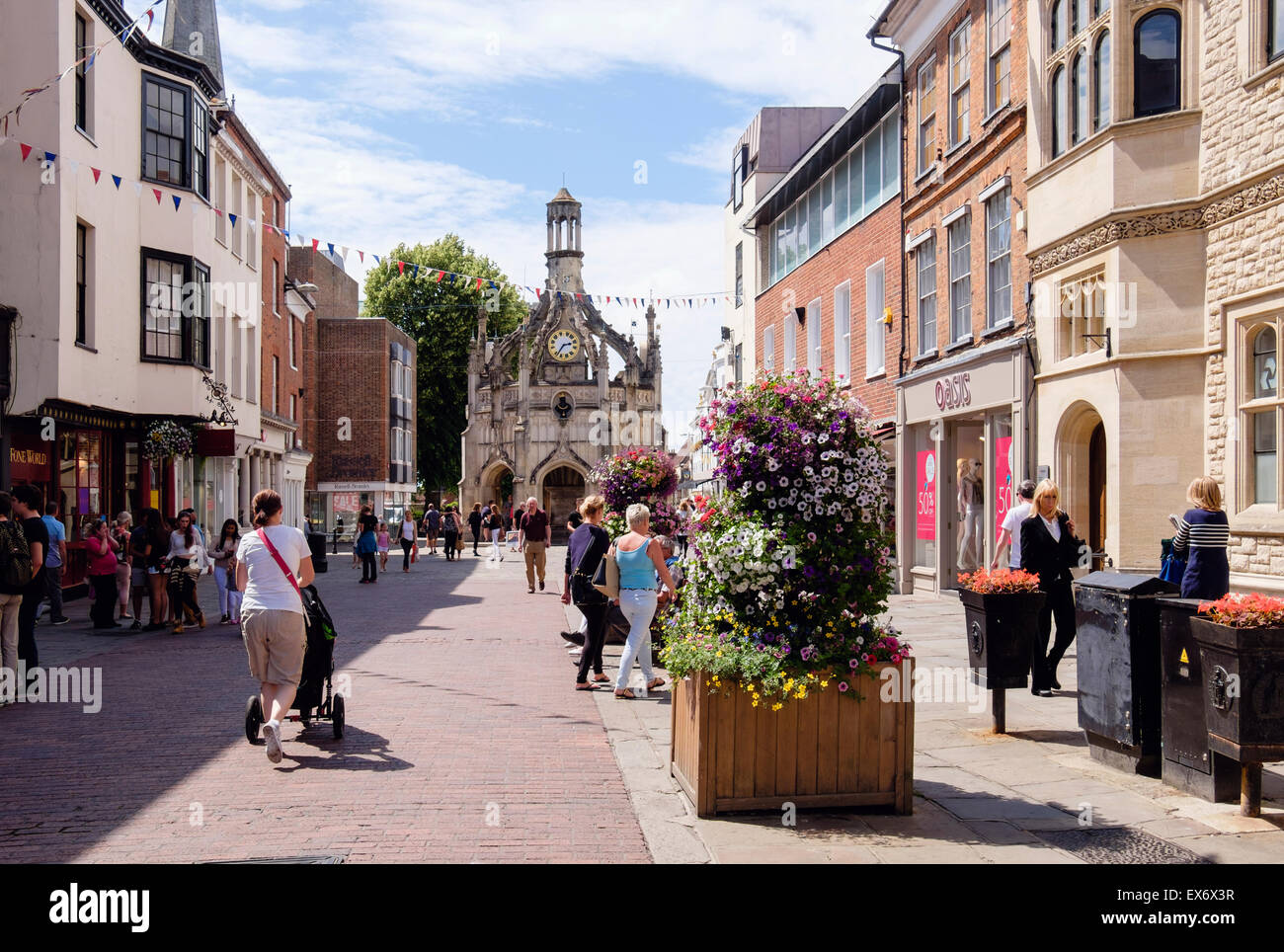 Street scene with view to old 16thc Market Cross with people shopping ...