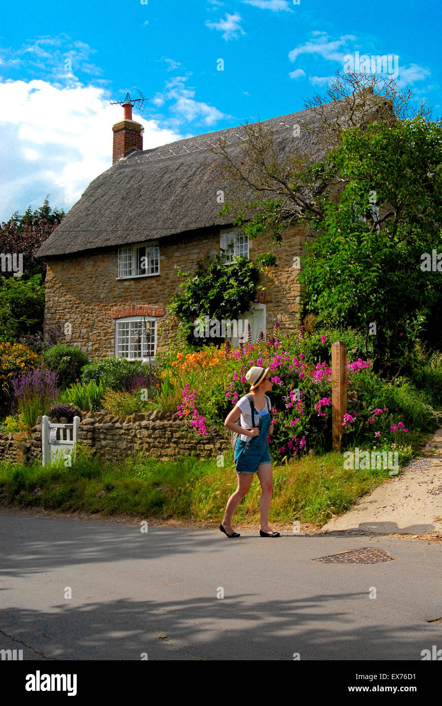 GIrl with back-pack passes thatched cottage, Abbotsbury, Dorset ...