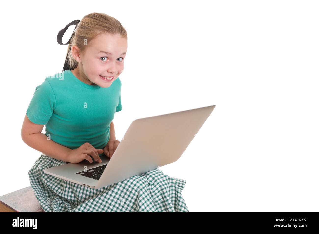 Young girl with a computer on her lap, giving a very cheeky smile to ...