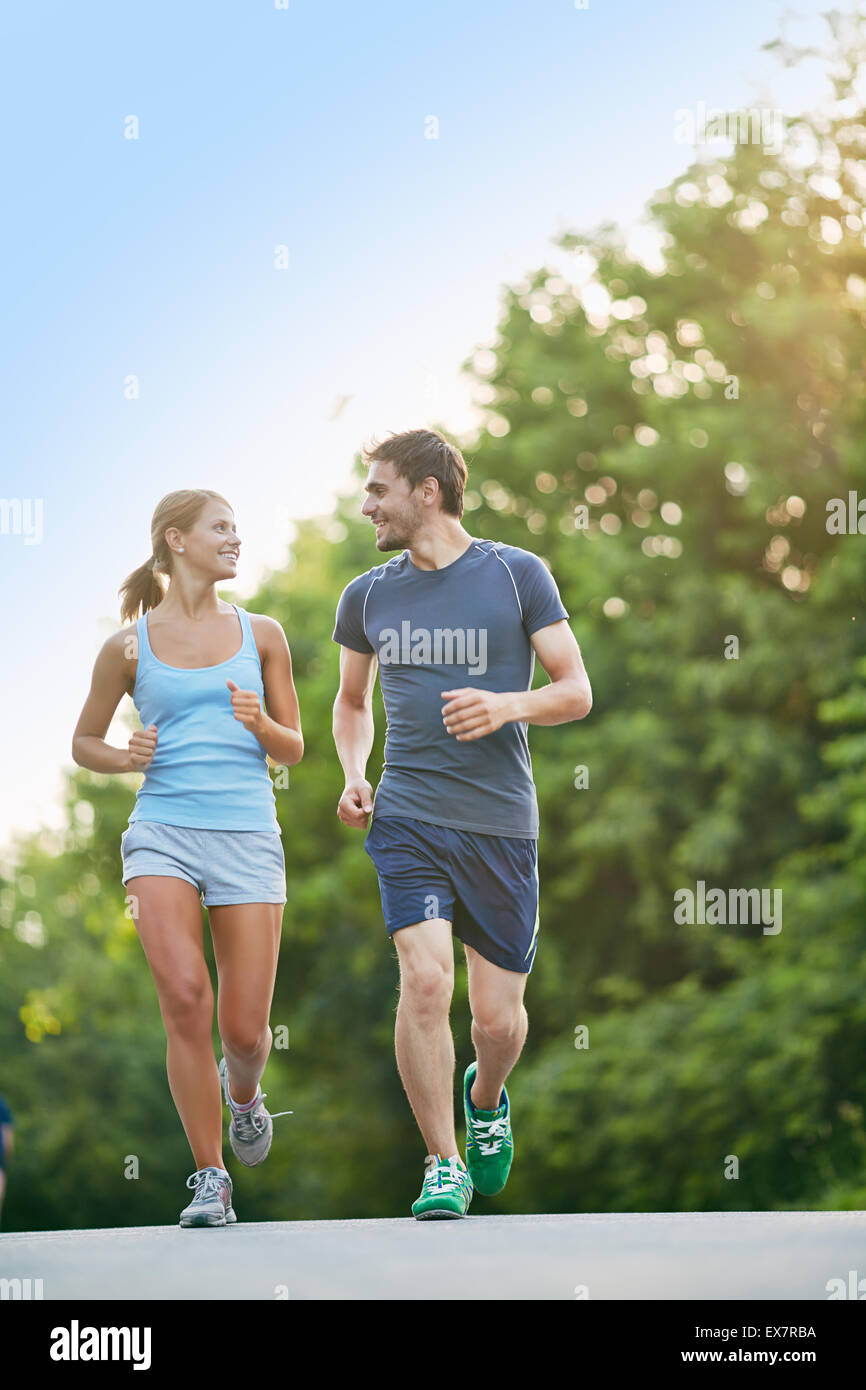 Happy couple running together in park Stock Photo - Alamy