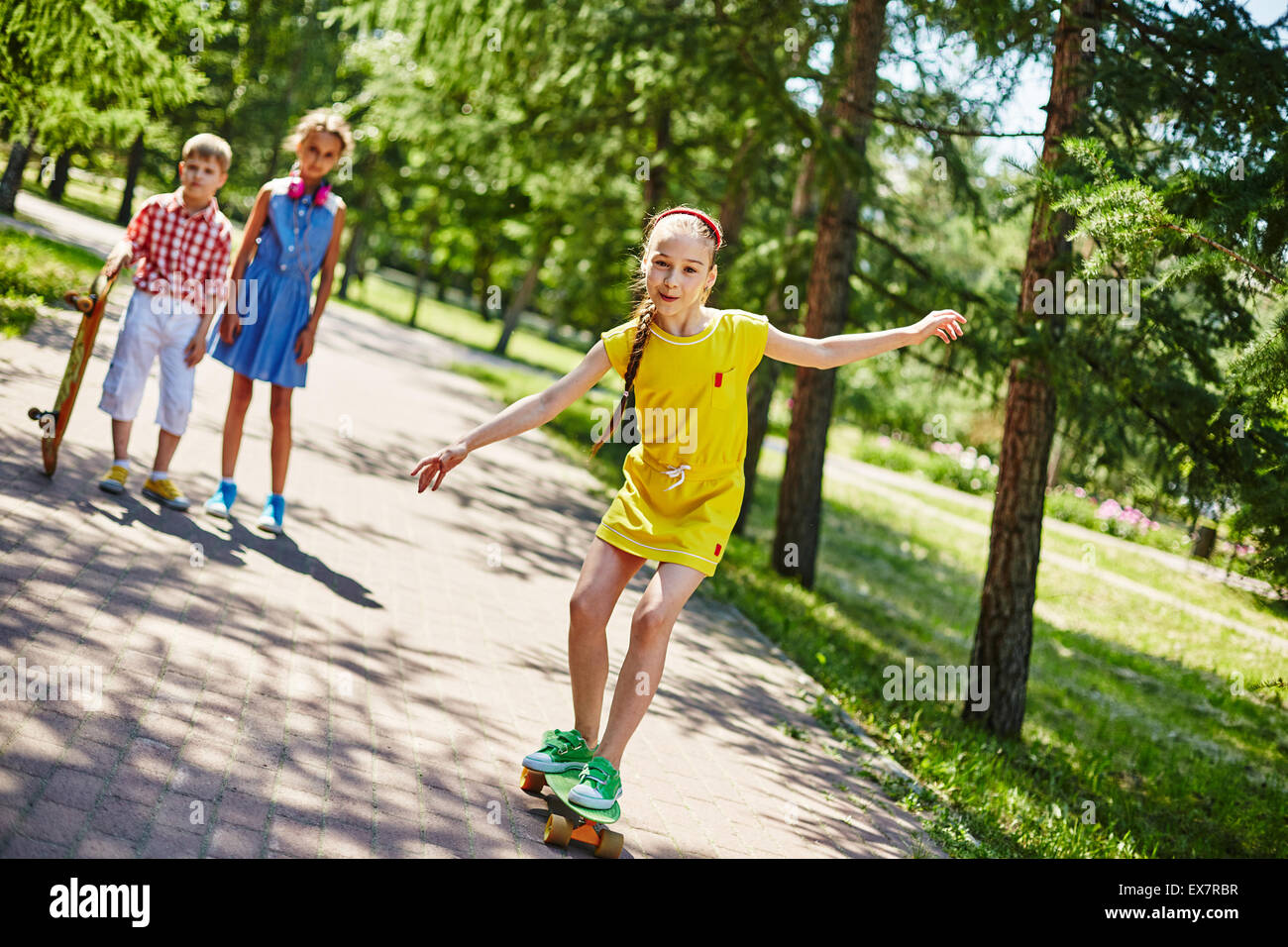 Happy girl skateboarding in park with her friends on background Stock ...