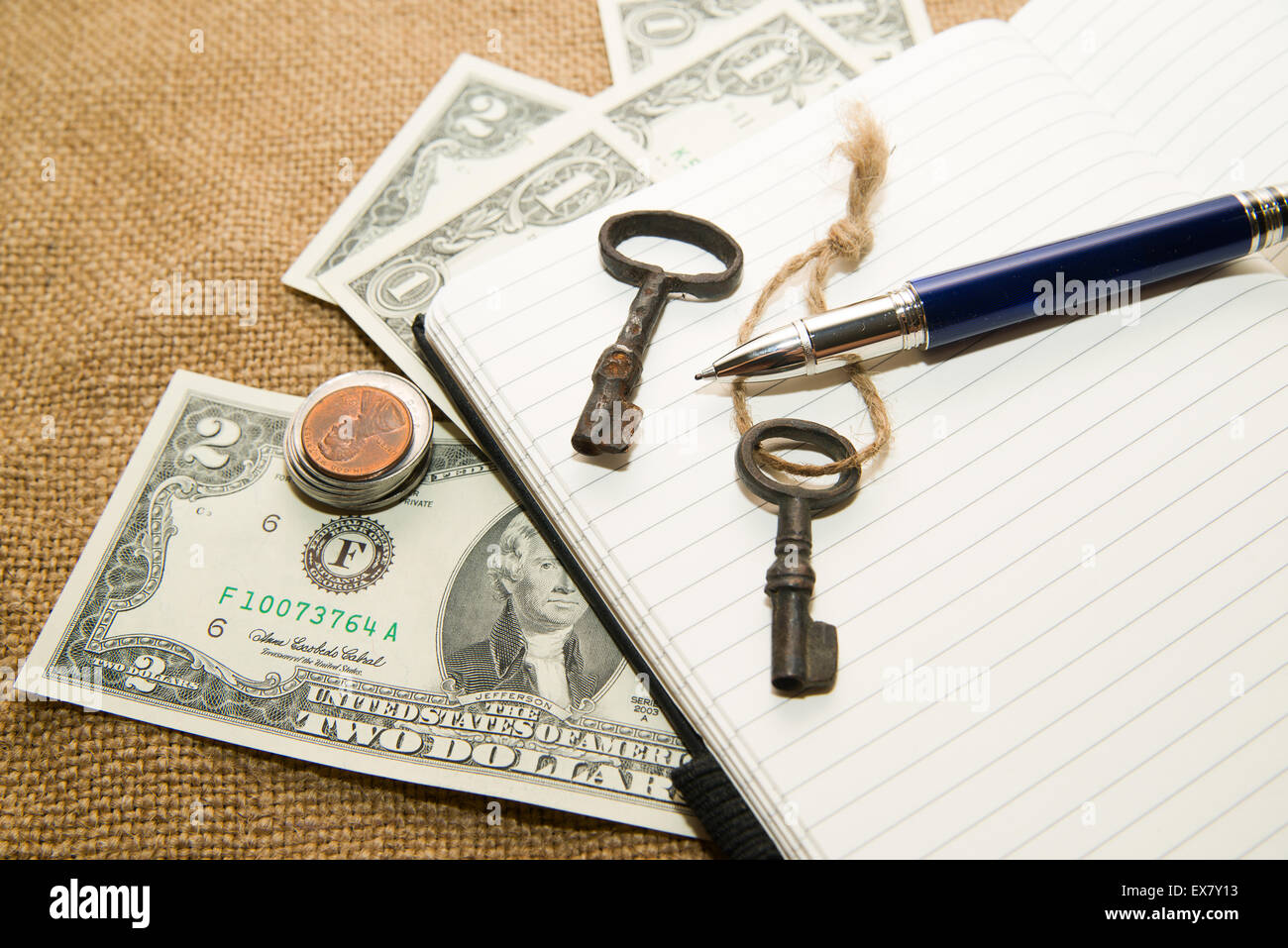 Opened notebook with a blank sheet, pen, keys and money on the old ...