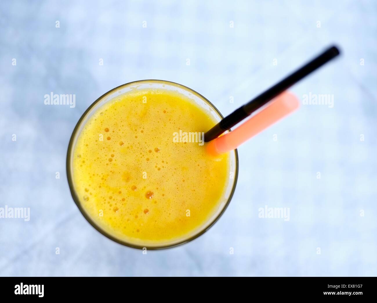 A glass of orange juice with straws taken from above Stock Photo - Alamy