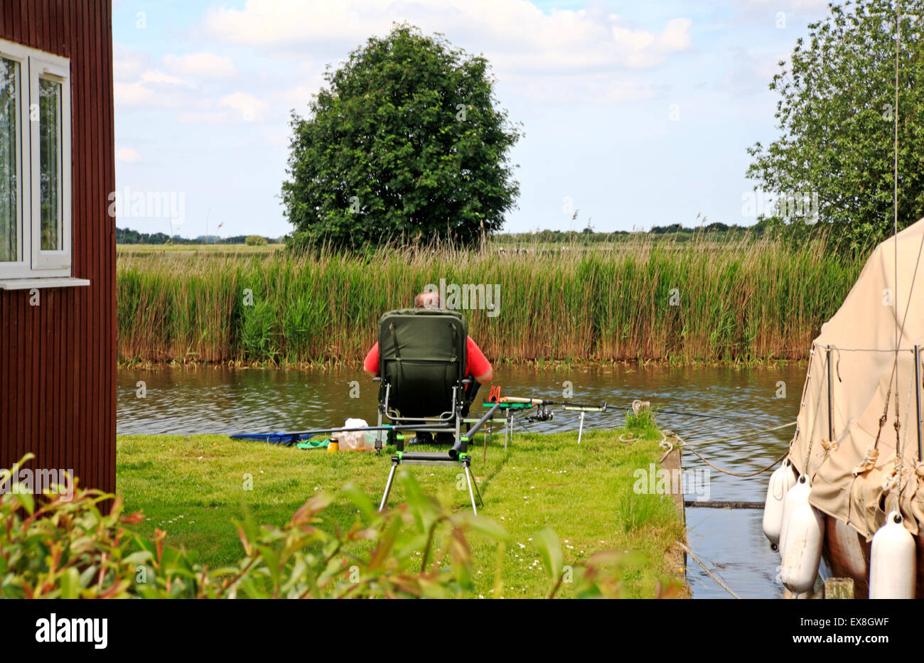 An angler fishing the River Thurne on the Norfolk Broads at Martham ...