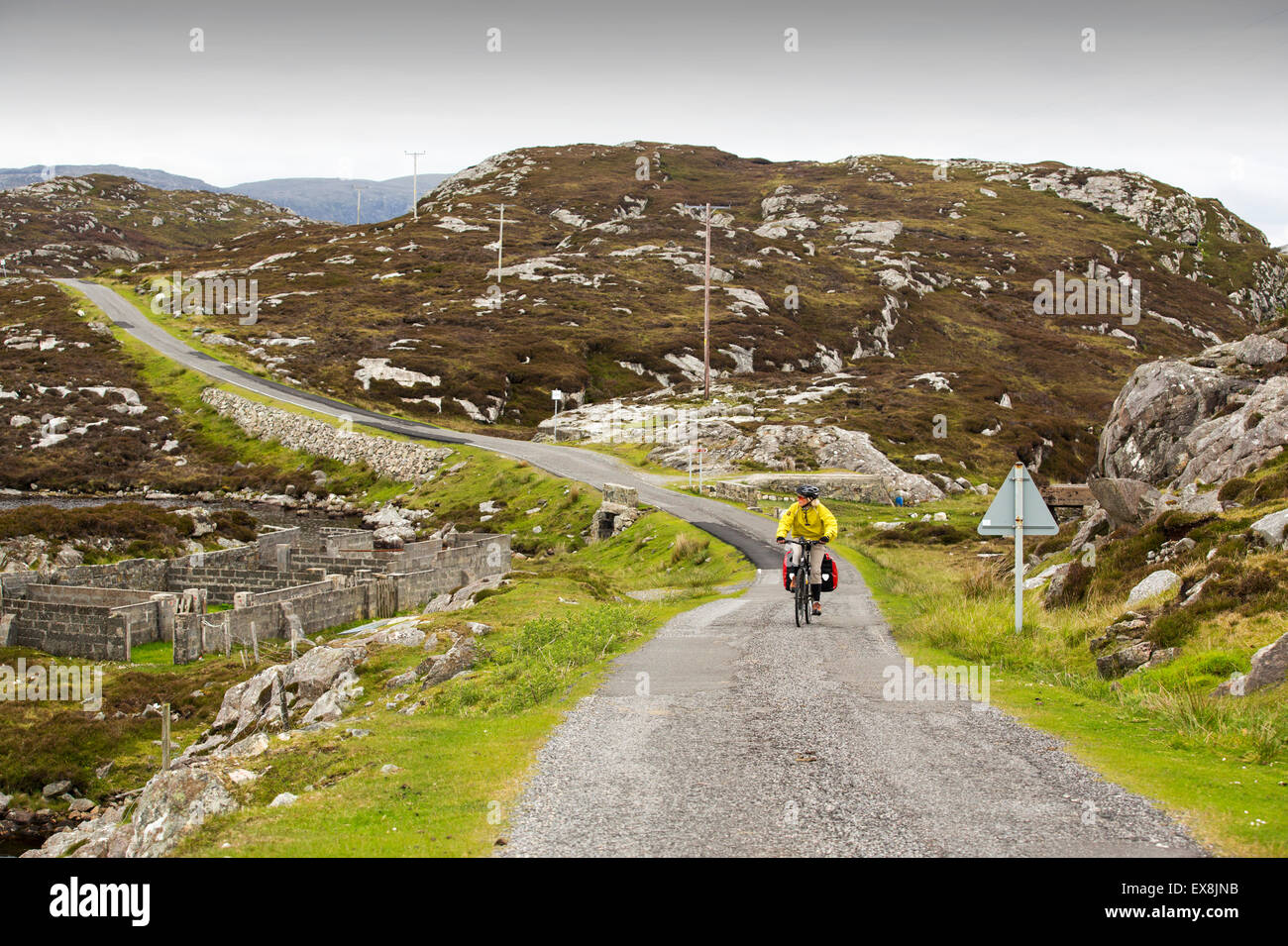 A woman cycle touring up the rugged Golden road on the East side of the ...
