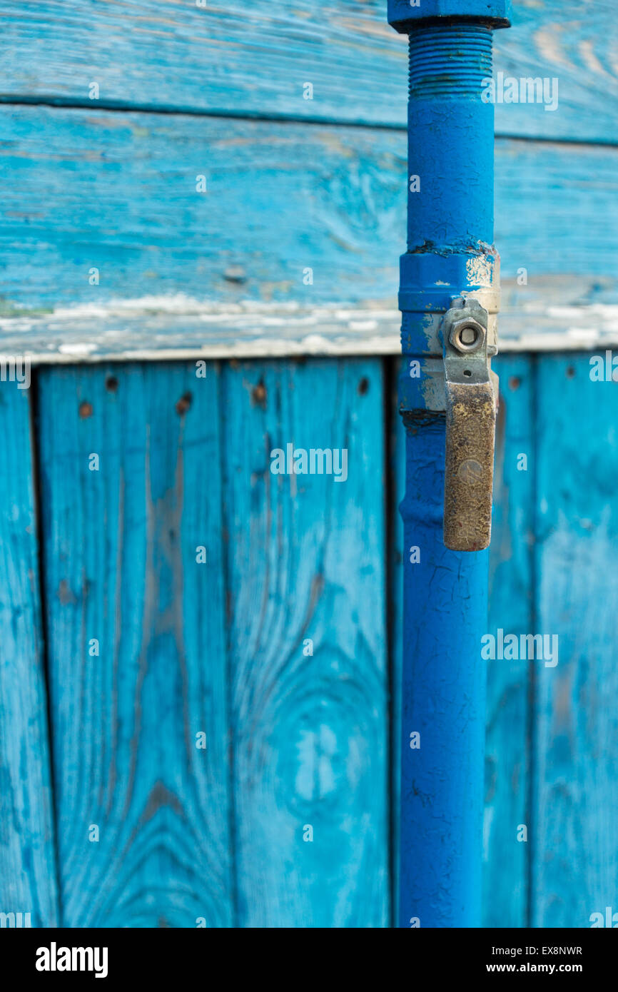 the blue gas pipe with the gate passes by a wooden wall Stock Photo - Alamy