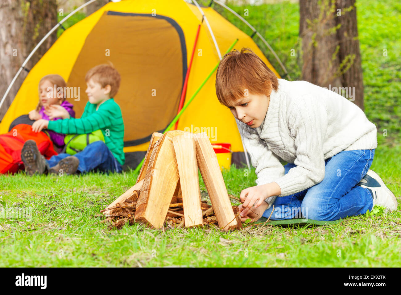 Boy prepares bonfire in forest with other children Stock Photo - Alamy