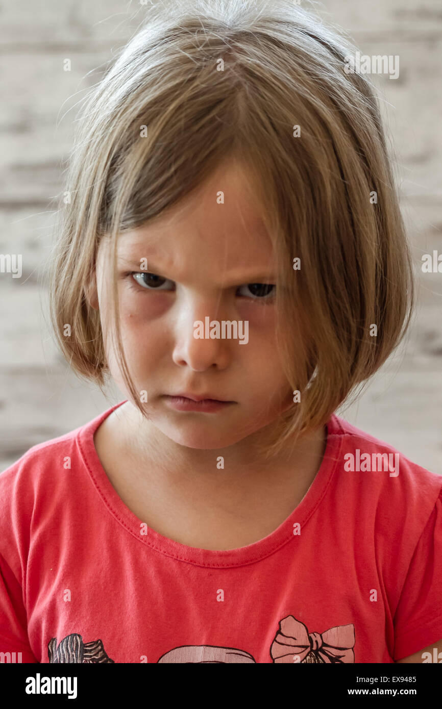 Very angry little girl in front of white wooden background Stock Photo ...