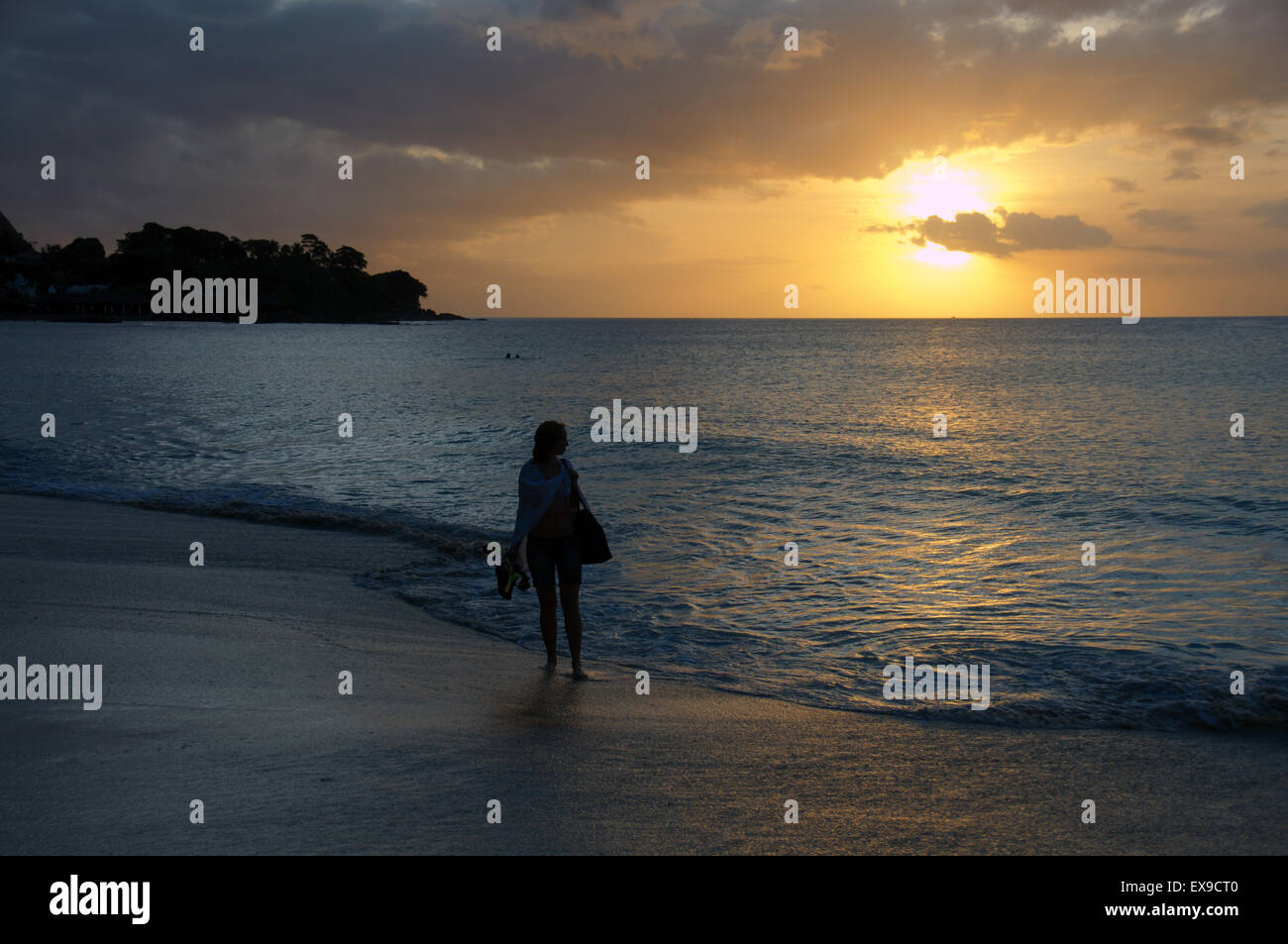 Young woman walking surf line the Indian Ocean surf at sunset ...