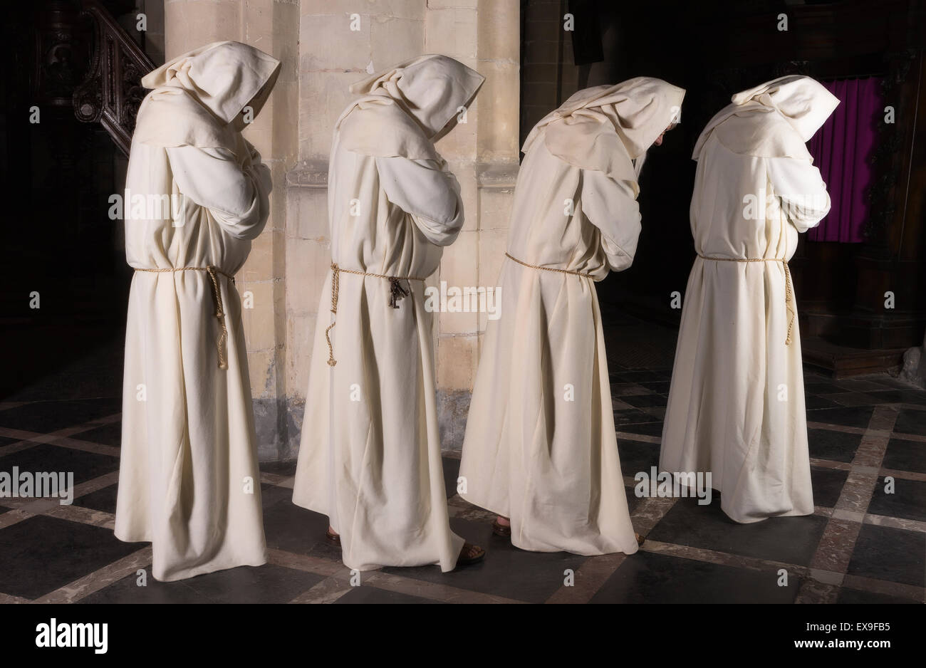 Four monks walking in a row along a pillar of a medieval church ...