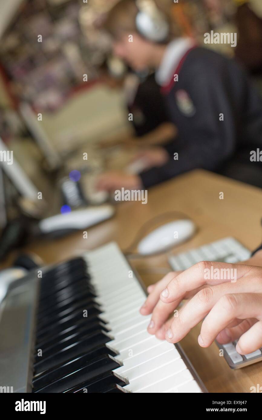 school students in uniform, utilising music software and equipment in ...
