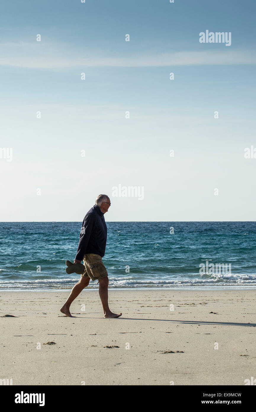 A holidaymaker walking across Sennen Beach in Cornwall Stock Photo - Alamy