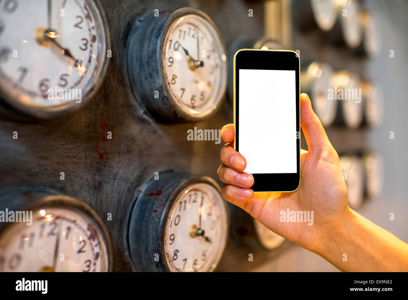 Female hand holding phone with white screen and metal clocks on ...