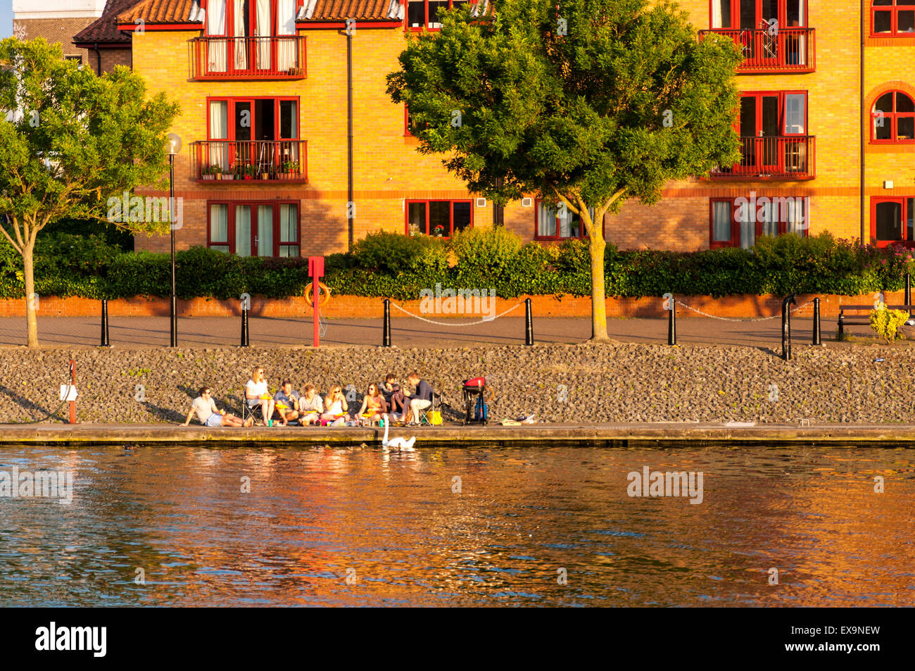 People enjoying a Summer evening picnic barbeque drink on harbourside ...
