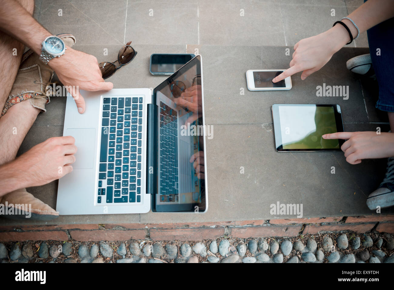 young couple using technology multitasking smarpthone tablet and ...