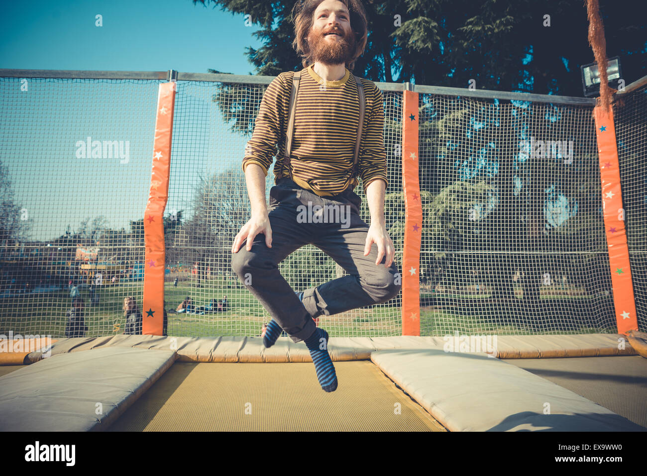 young bearded stylish handsome hipster man jumping on trampoline at ...