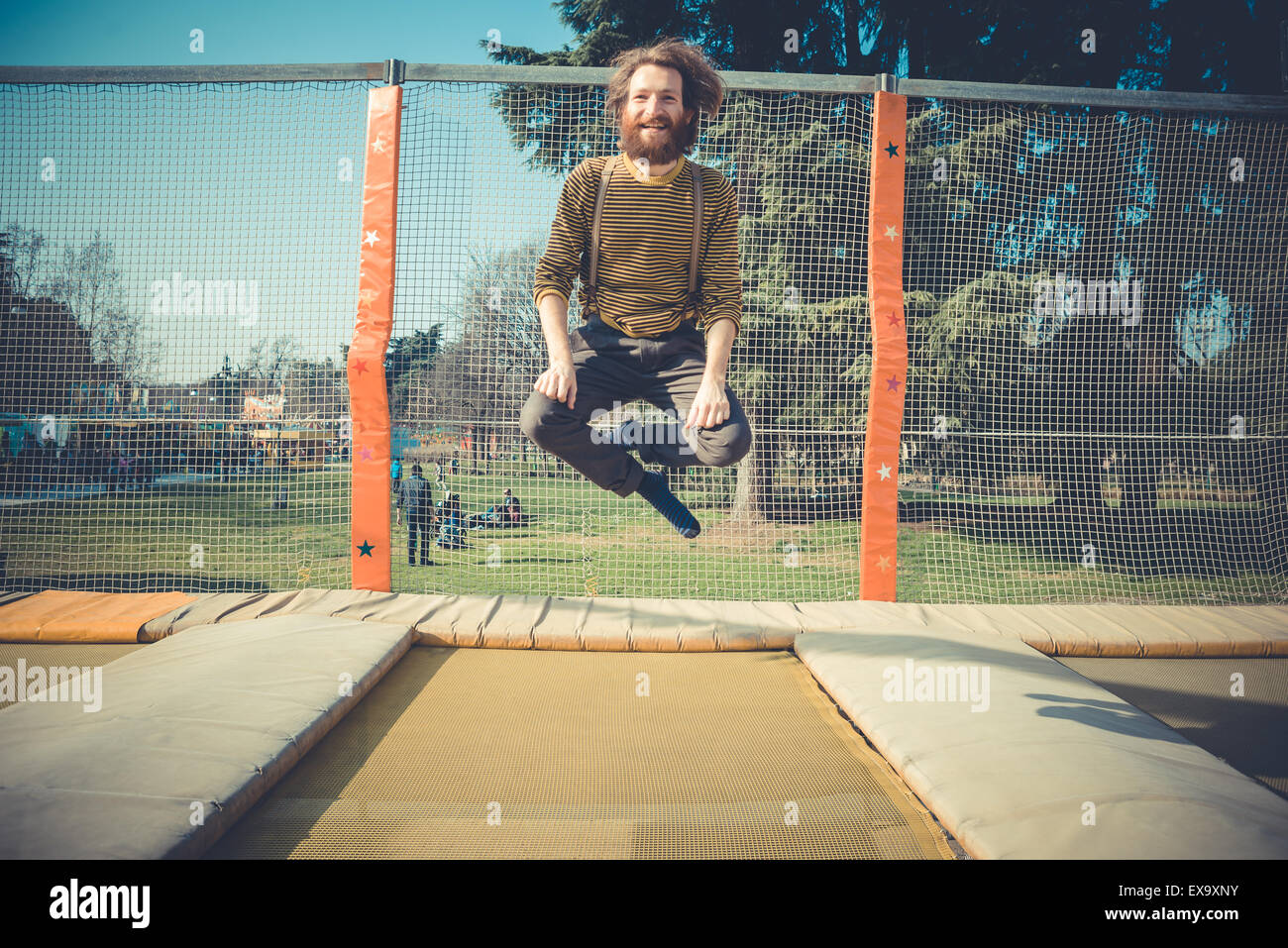 young bearded stylish handsome hipster man jumping on trampoline at ...