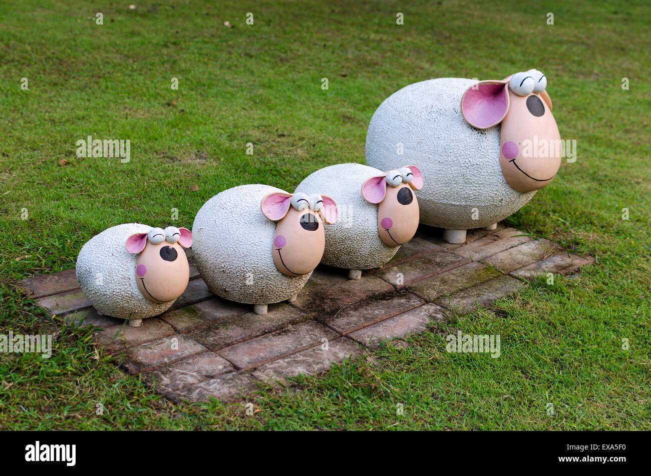 Smile white sheep statue in green grass Stock Photo - Alamy