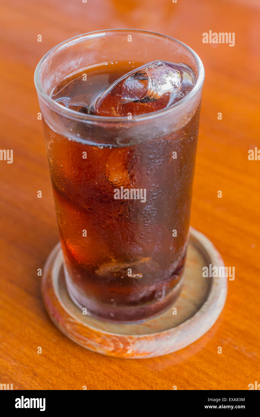 Glass of soft drink with ice on wooden plank Stock Photo - Alamy