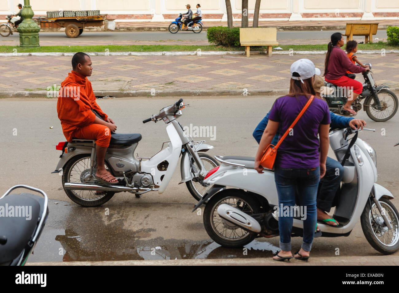 A Buddhist monk sitting on a parked motorcycle near bus station in ...