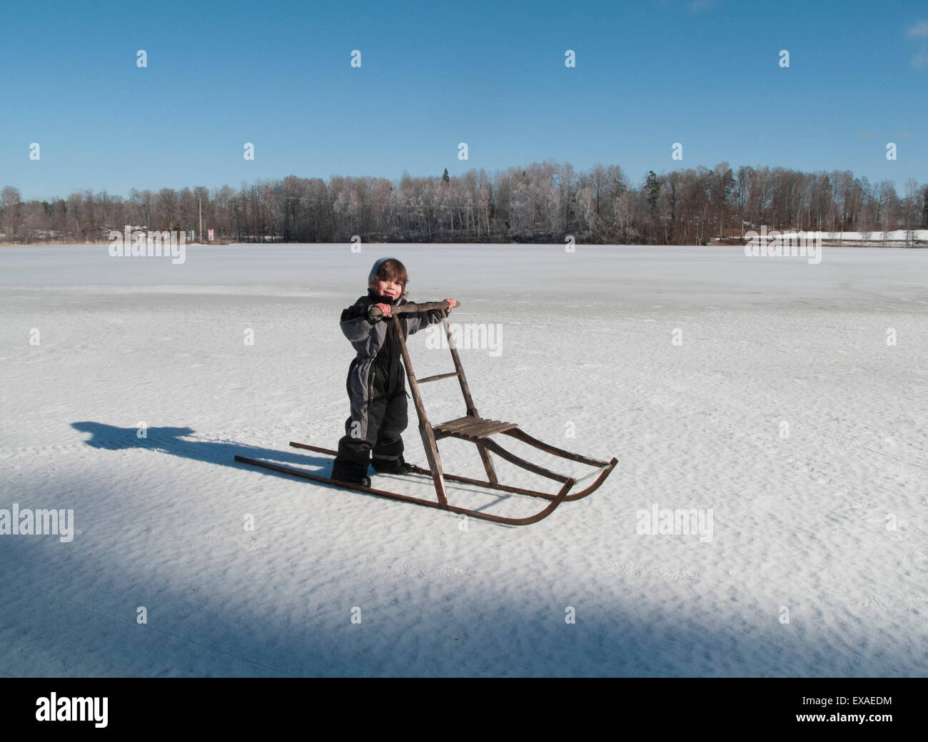 A boy with a kick-sledge on a frozen lake Stock Photo - Alamy