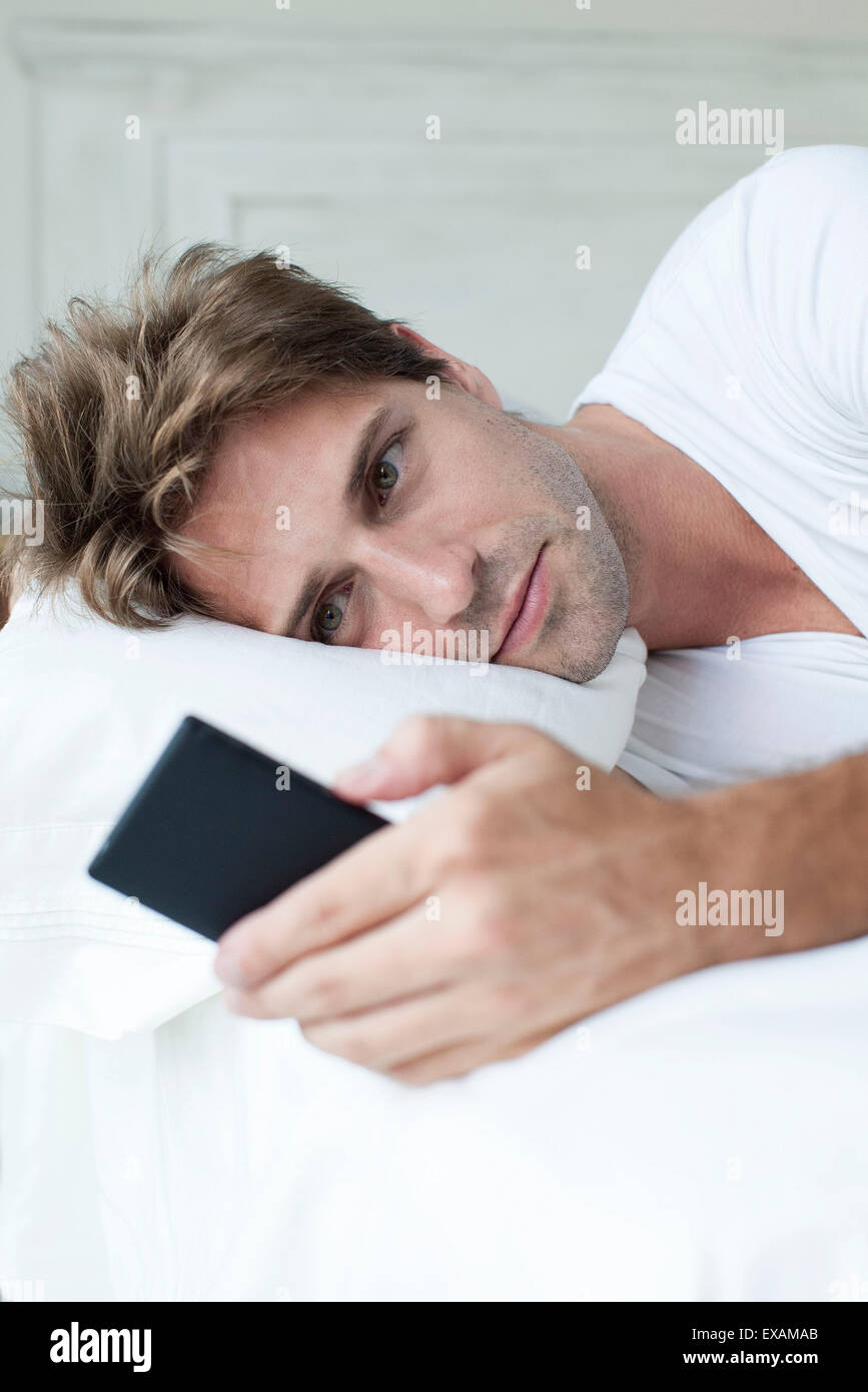 Man lying in bed using smartphone Stock Photo - Alamy