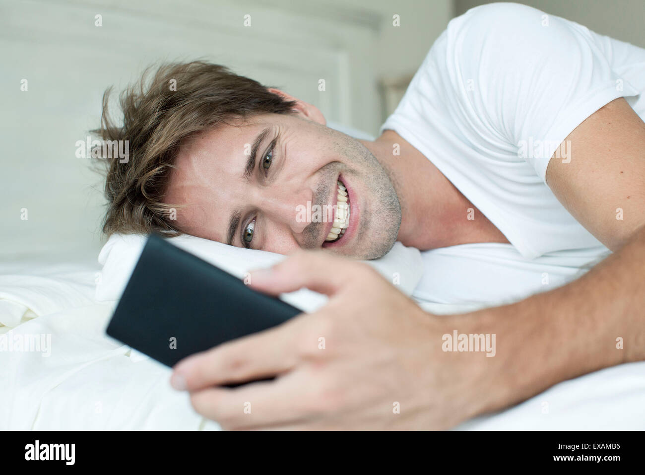 Man in bed using smartphone Stock Photo - Alamy