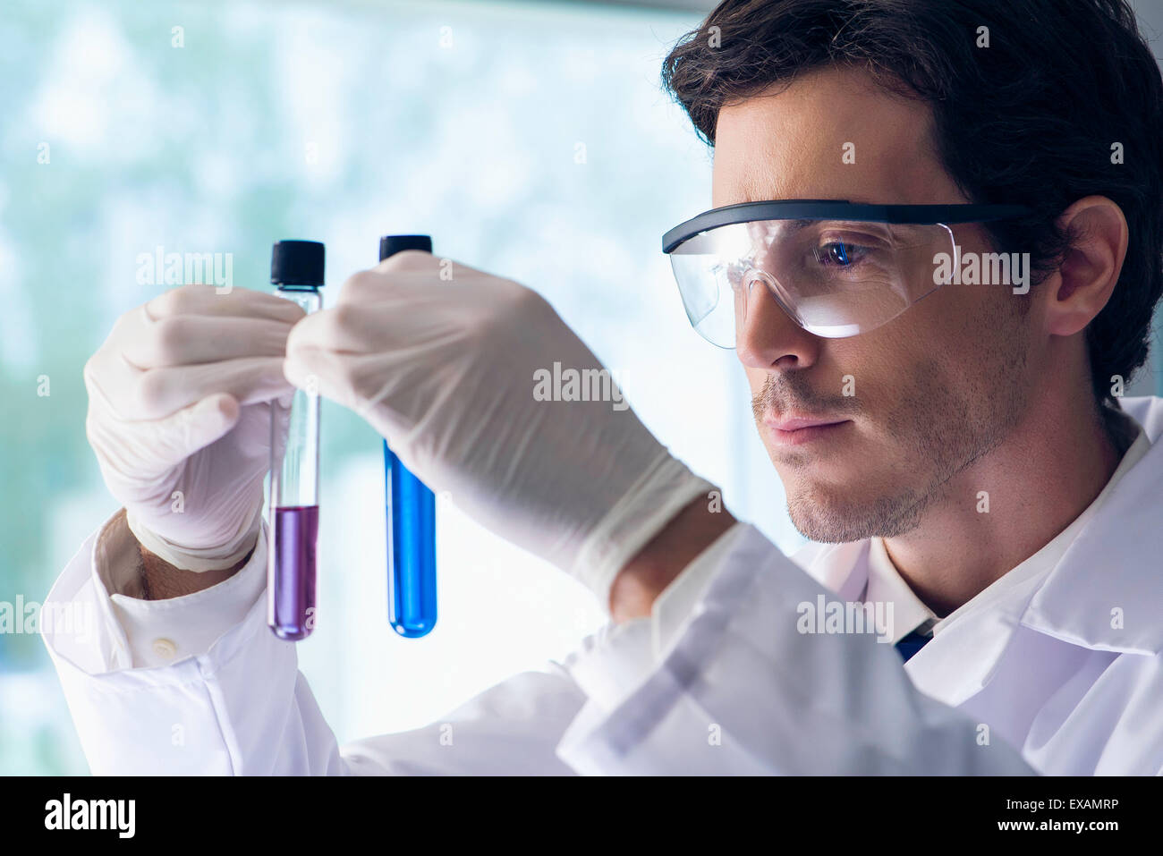 Scientist scrutinizing test tubes in lab Stock Photo - Alamy