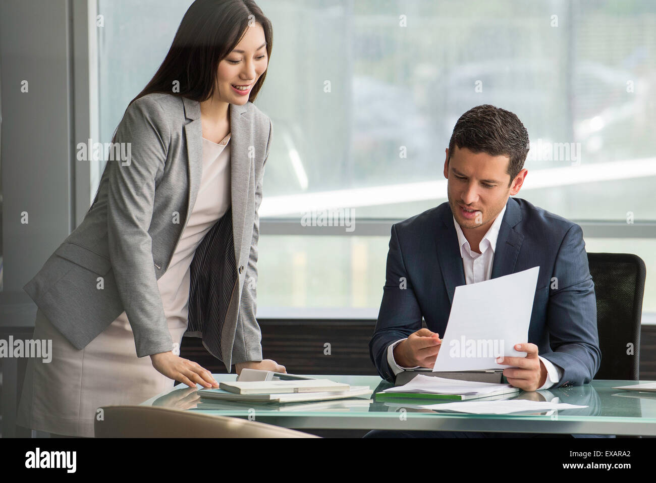Executive reviewing document with assistant Stock Photo - Alamy