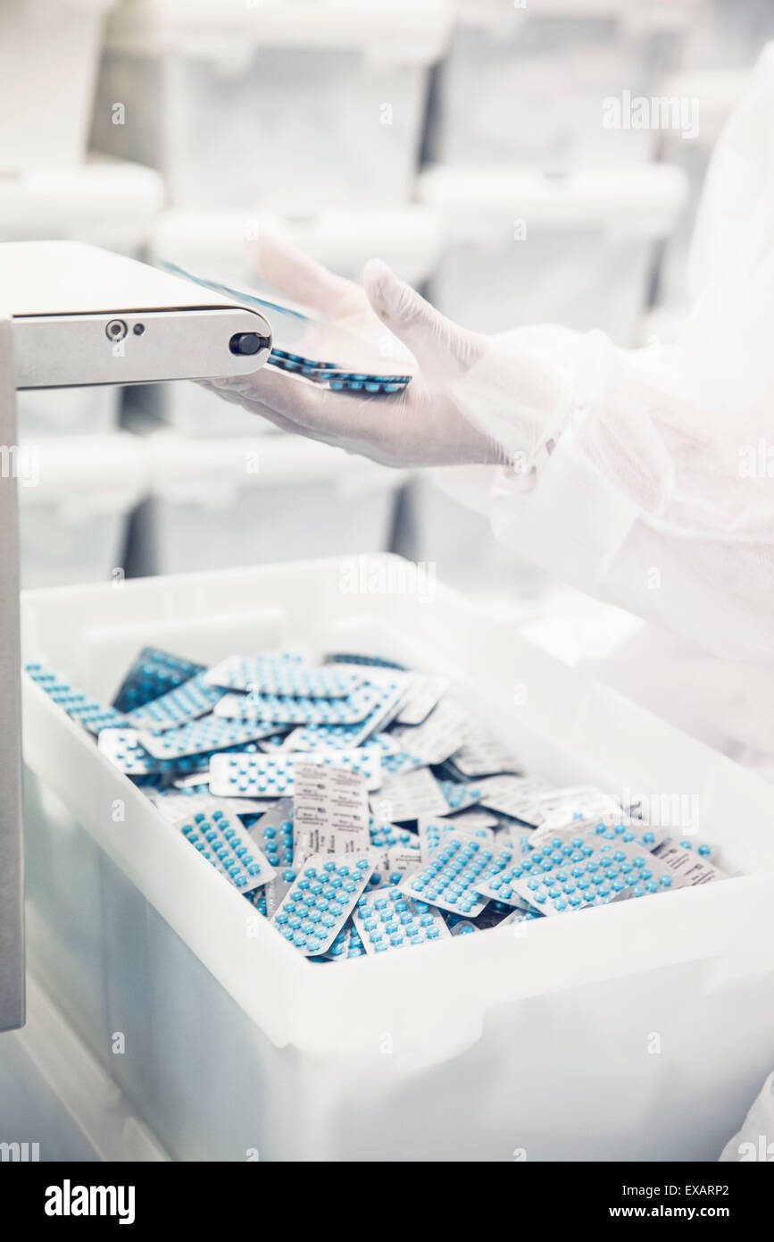 Worker packaging pill packets exiting production equipment Stock Photo ...