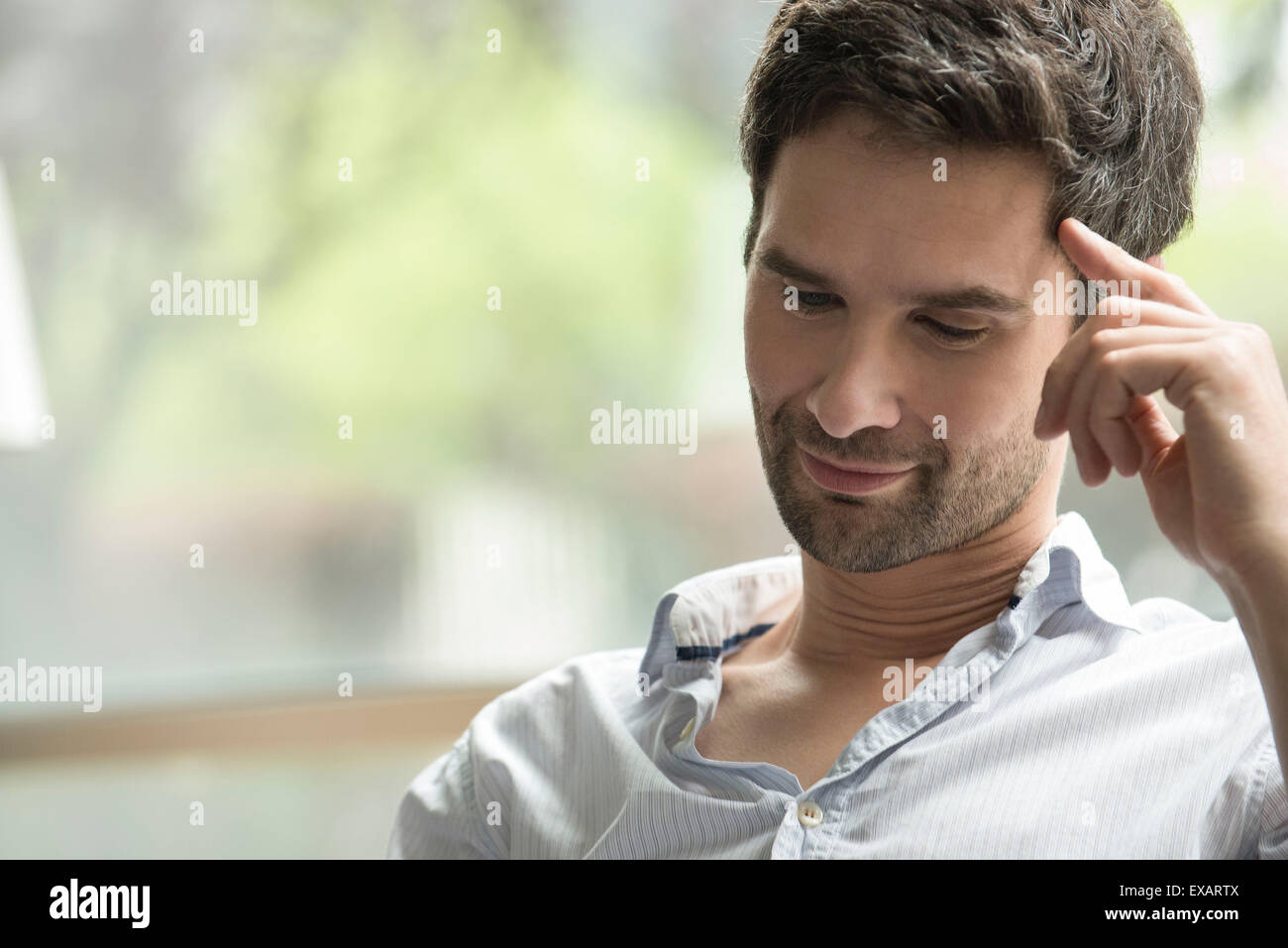 Man looking down attentively with finger pressed against temple Stock ...