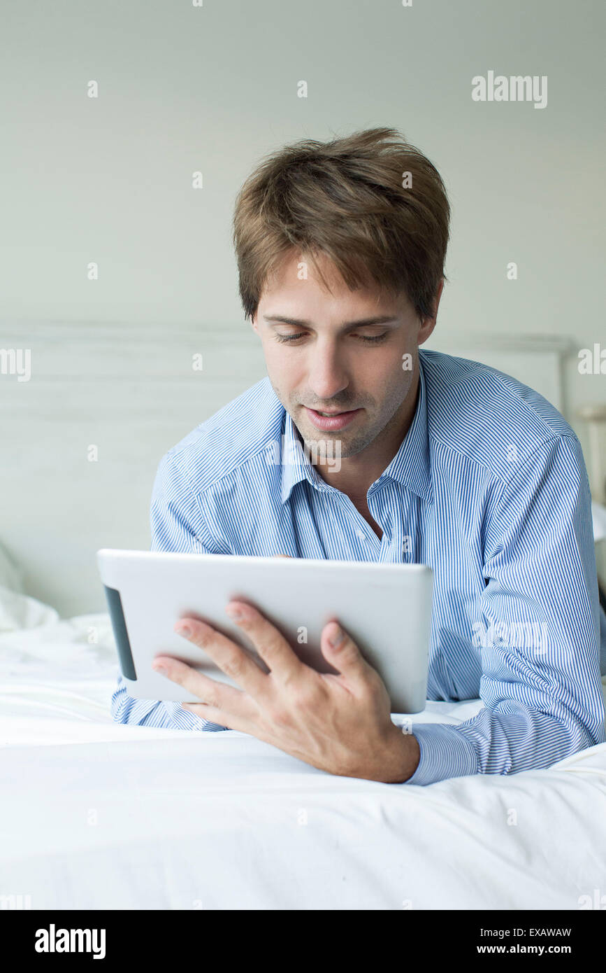 Man lying in bed using digital tablet Stock Photo - Alamy