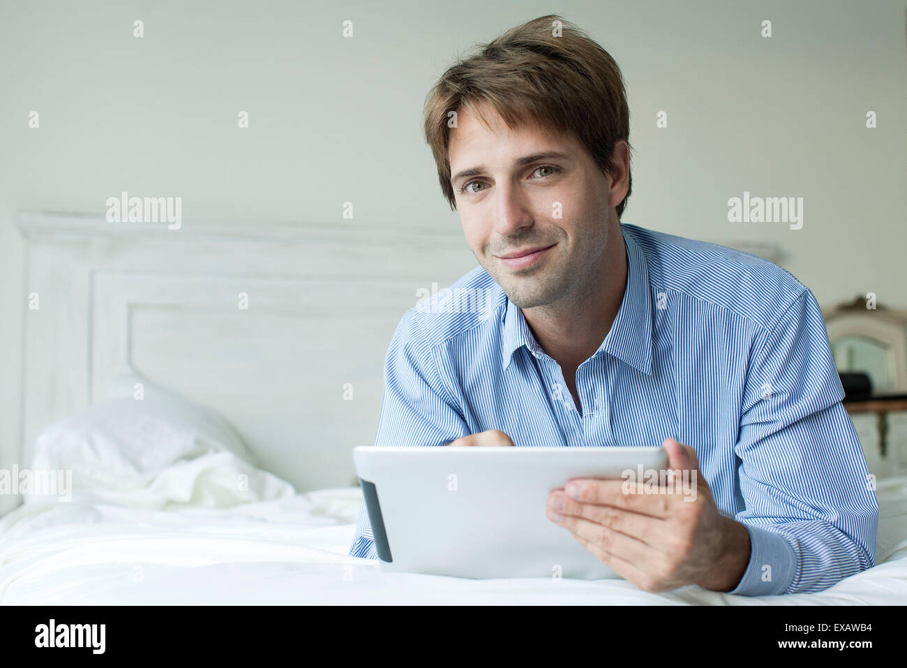 Man lying in bed using digital tablet Stock Photo - Alamy