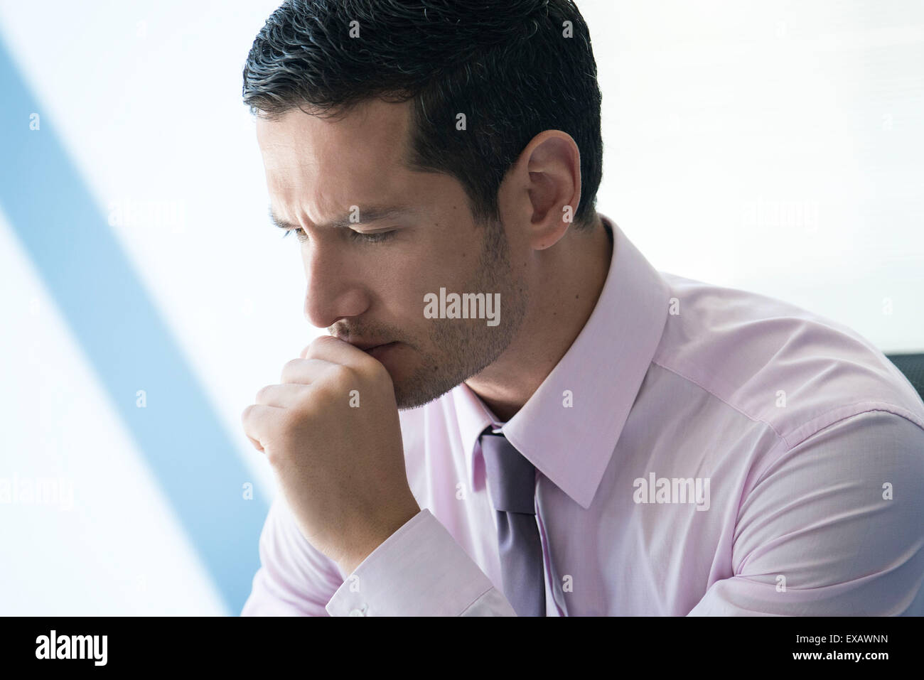 Businessman with hand under chin with look of concern Stock Photo - Alamy