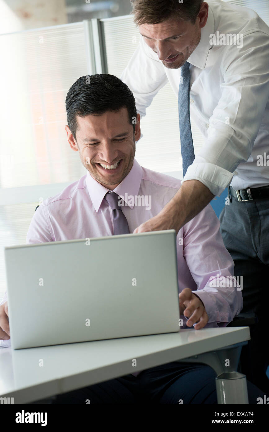 Office workers looking at computer together laughing Stock Photo - Alamy