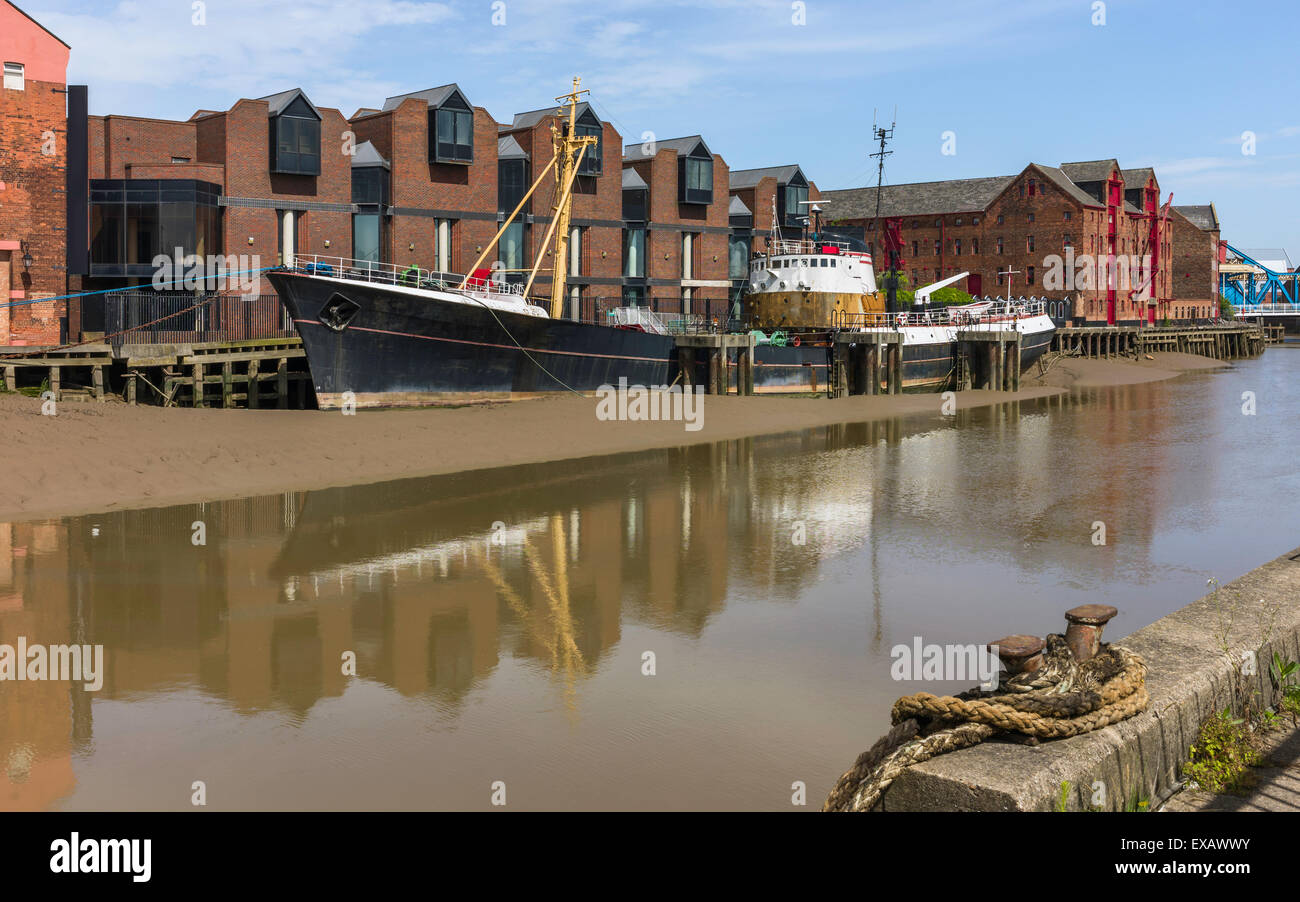 Obsolete ship beached on mud bank of river Hull with view of quayside ...