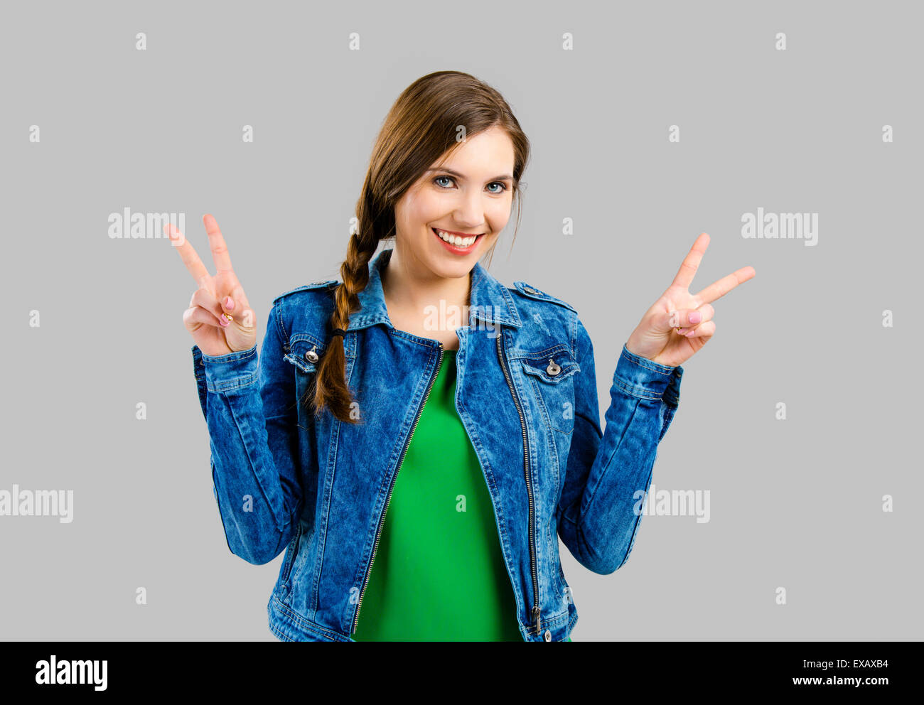 Portrait of a beautiful woman with fingers up, isolated over grey ...