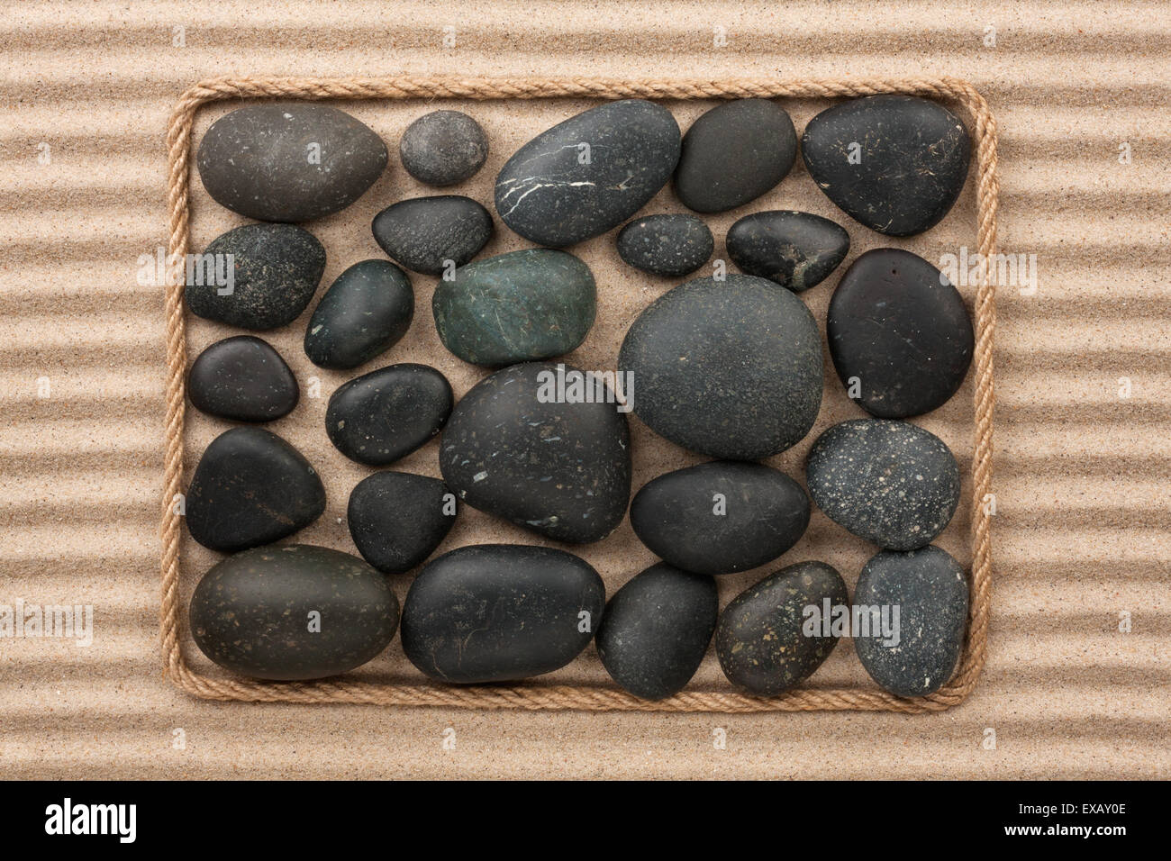Frame made of rope with black stones on the wavy sand Stock Photo - Alamy