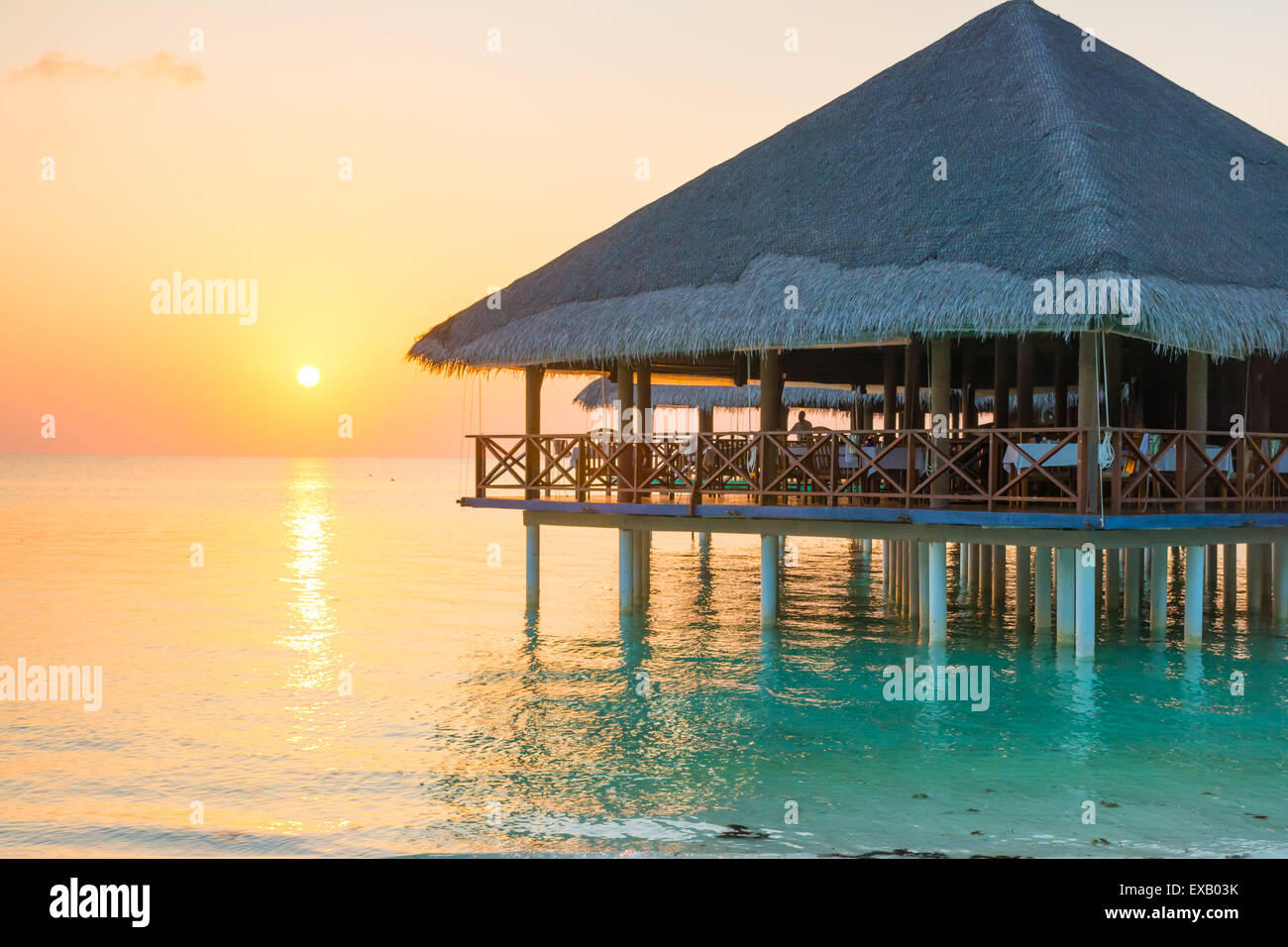 Sunset and overwater restaurant of an island resort Stock Photo - Alamy
