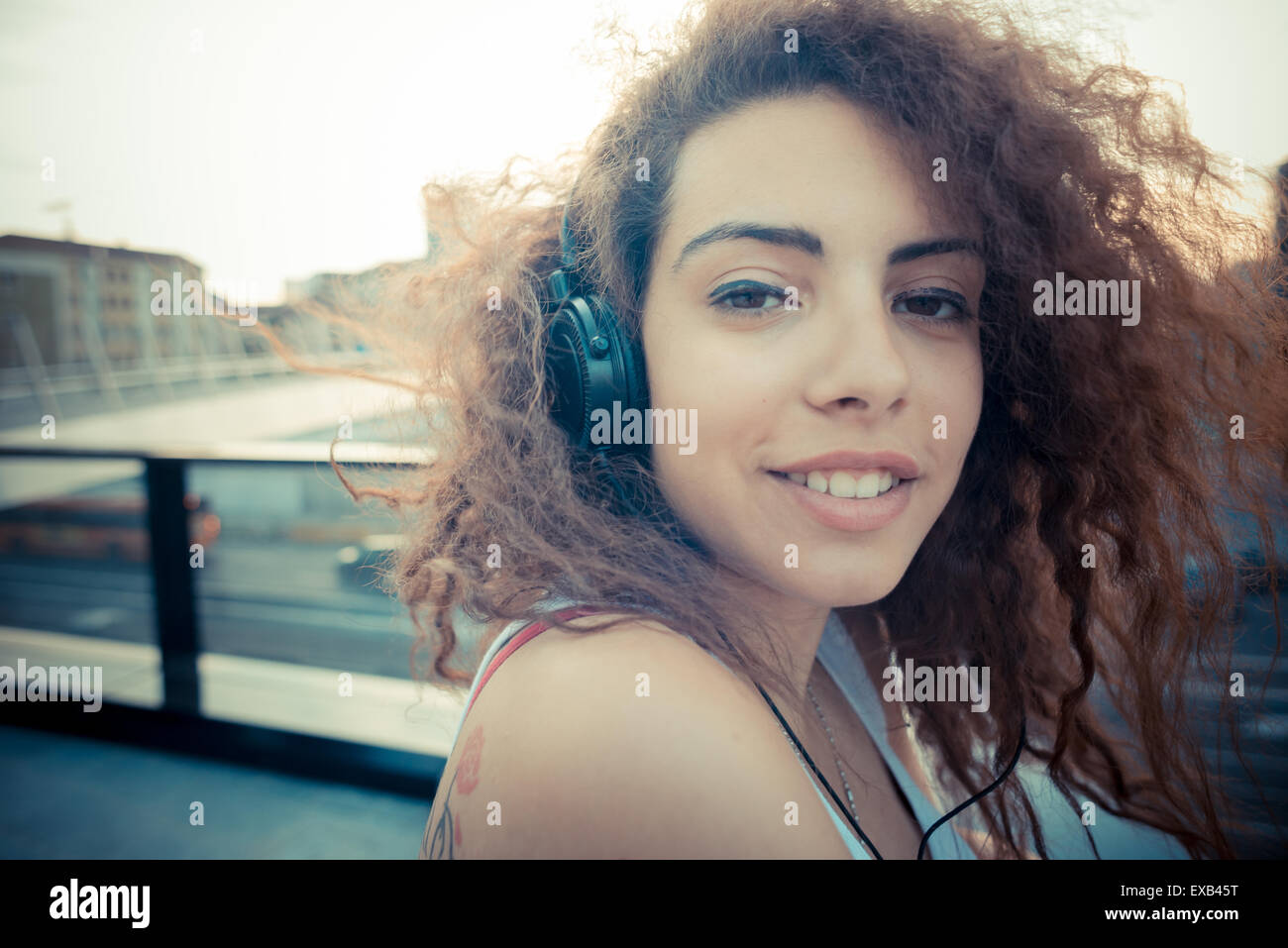 young beautiful long curly hair hipster woman listening to music with ...