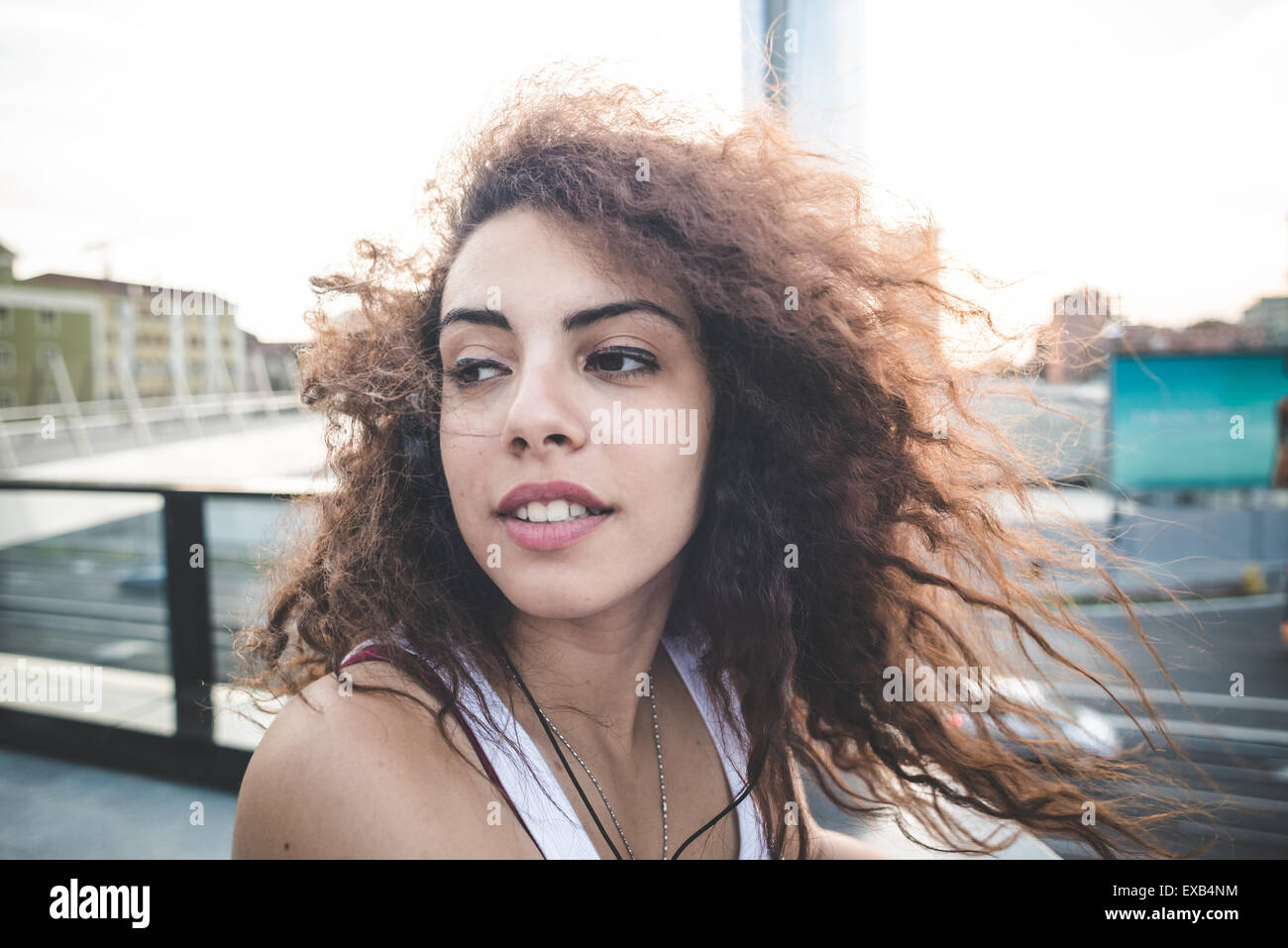 young beautiful long curly hair hipster woman listening to music with ...