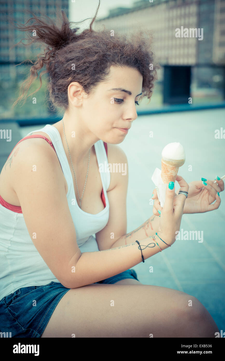 young beautiful long curly hair hipster woman eating ice cream in the ...