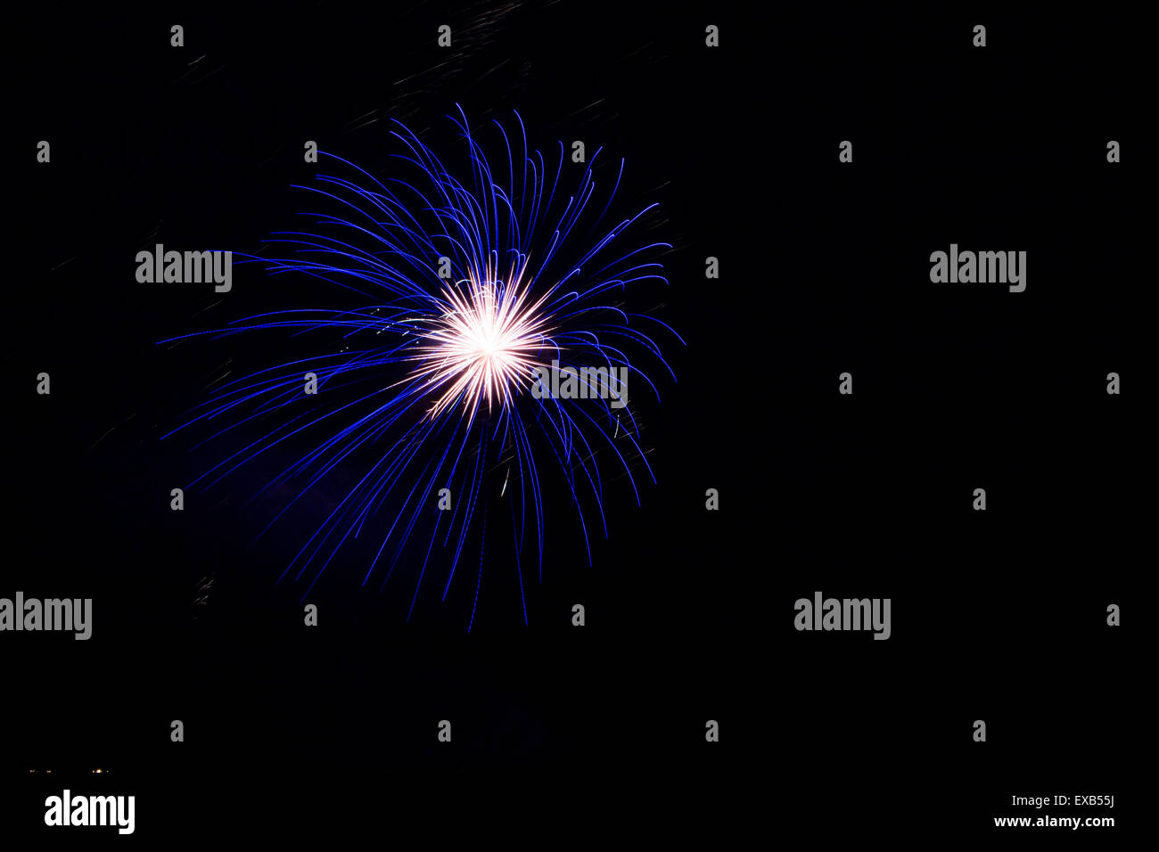 A single blue and white firework just starts to explode as this image ...