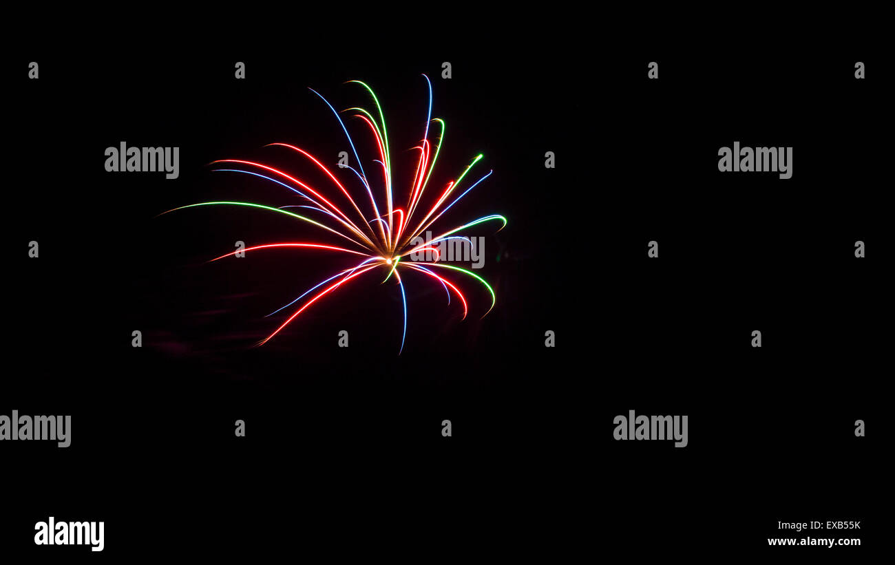 A single firework spreads a brilliant neon stream of colors out from ...