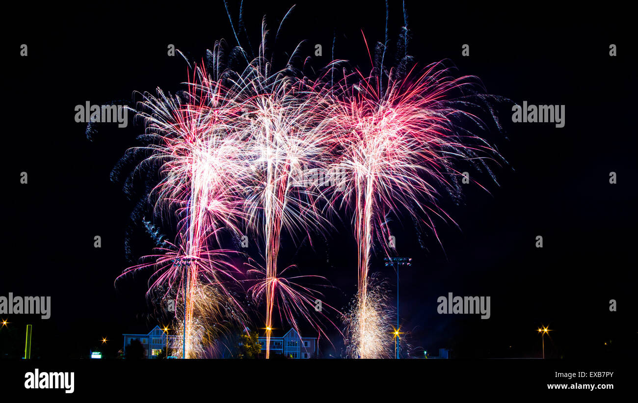 Fireworks explode brightly with houses in the background being lit by ...