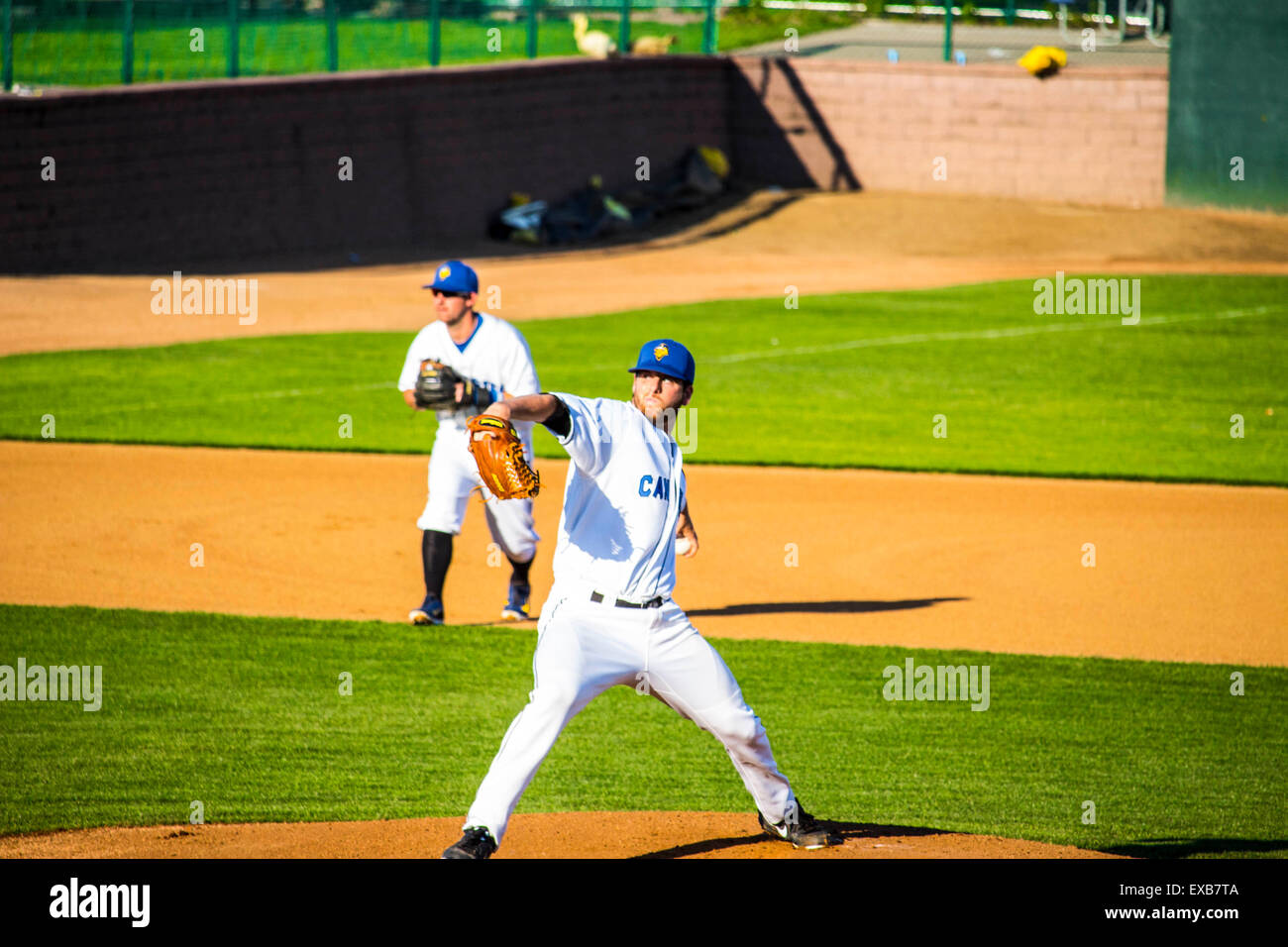 A baseball pitcher winds up and prepares to throw while the short stop ...