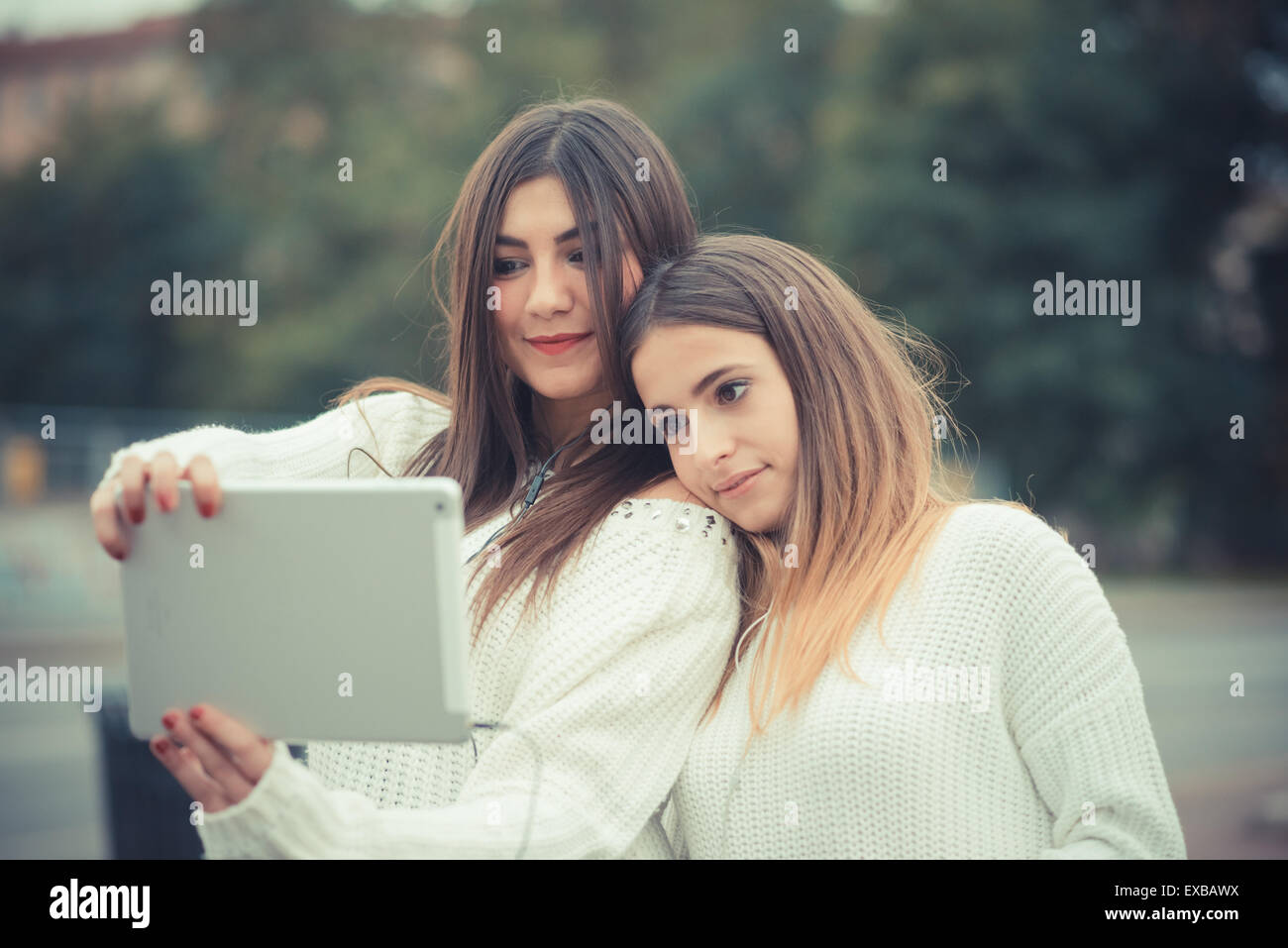young couple beautiful women girls autumn using tablet outdoor Stock ...