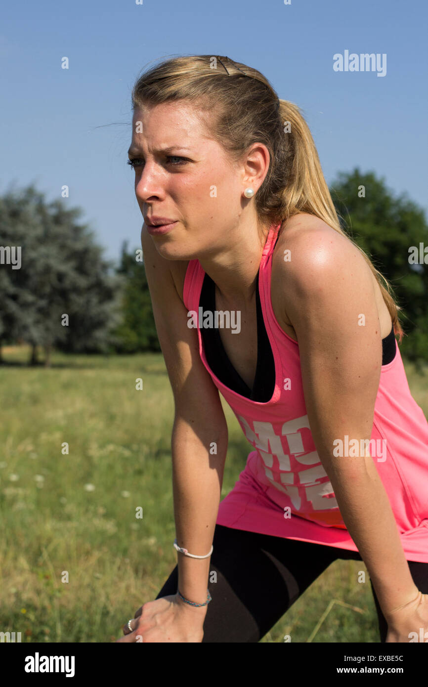 Blonde girl tired during a running training session at the park in the ...