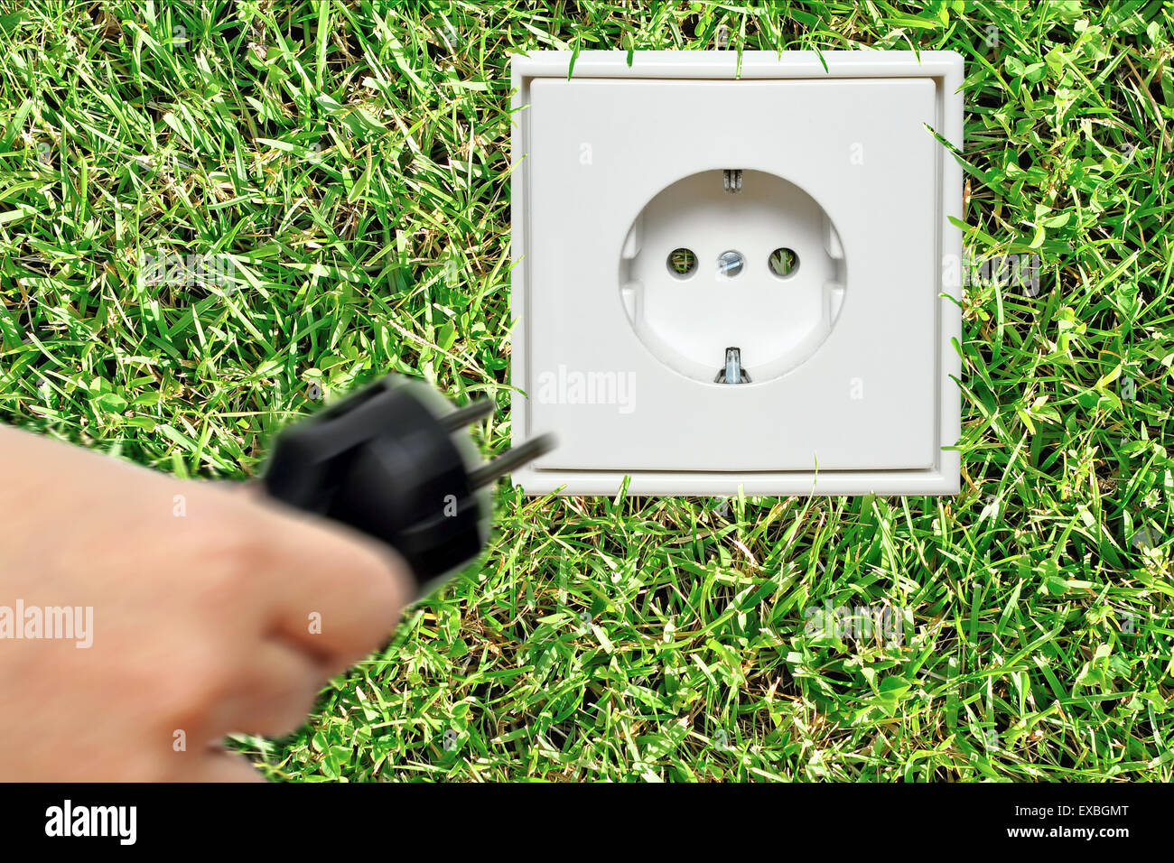 Hand connecting a plug to a socket on grass Stock Photo - Alamy